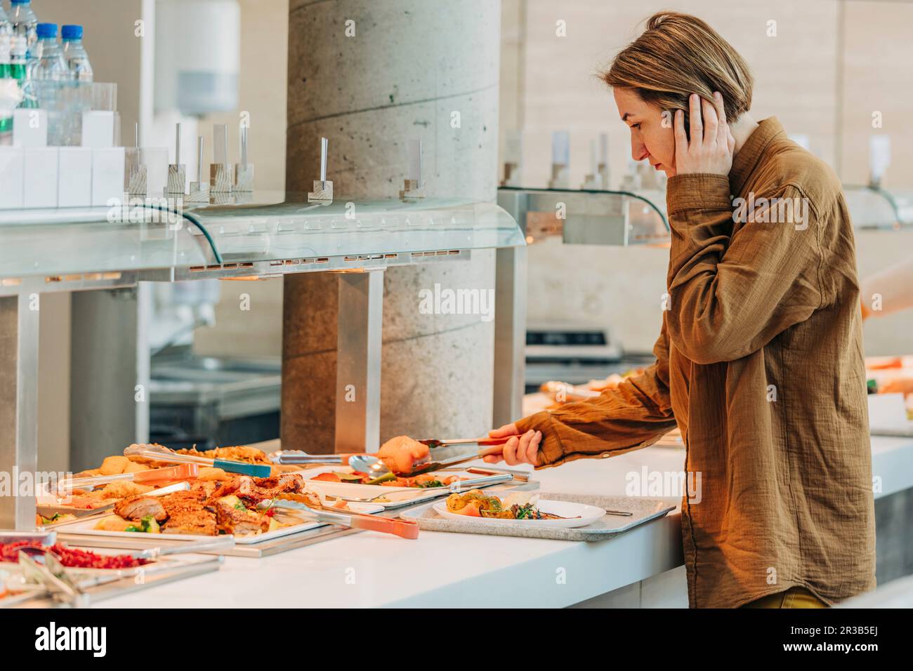 Woman taking food in plate standing by buffet Stock Photo - Alamy