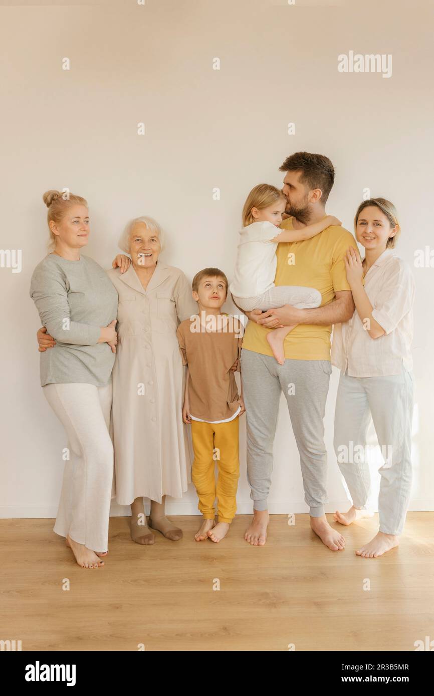 Happy multi-generation family standing together in front of wall at ...