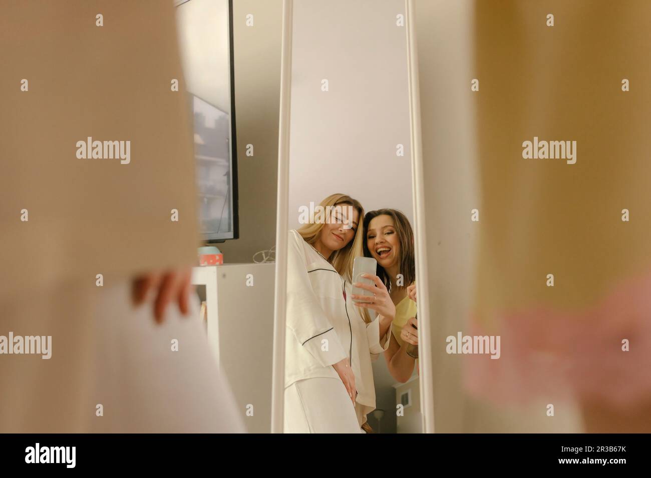 Friends taking mirror selfie through smart phone at home Stock Photo ...