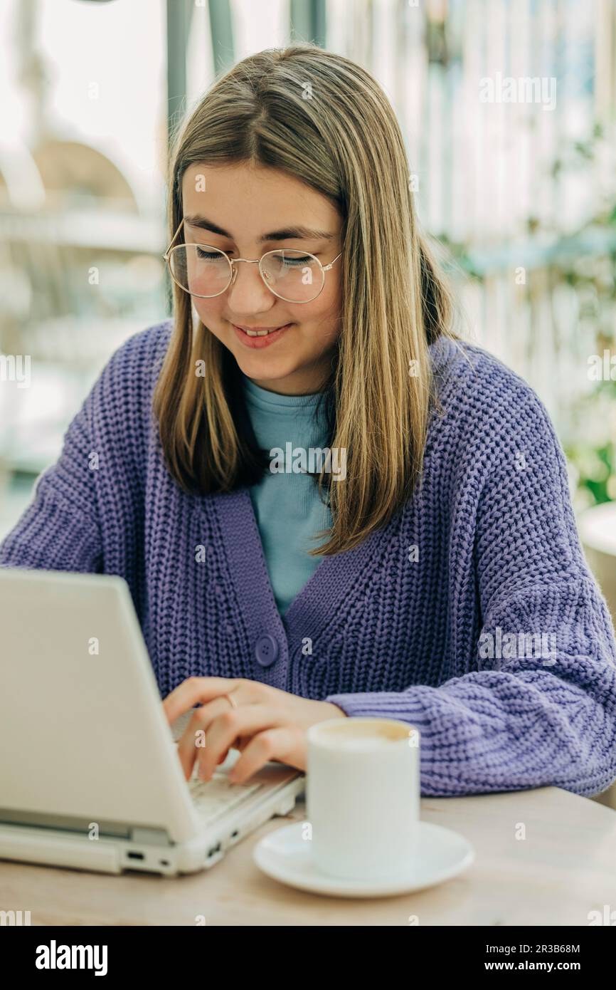 Teenage girl using laptop sitting at school cafeteria Stock Photo - Alamy