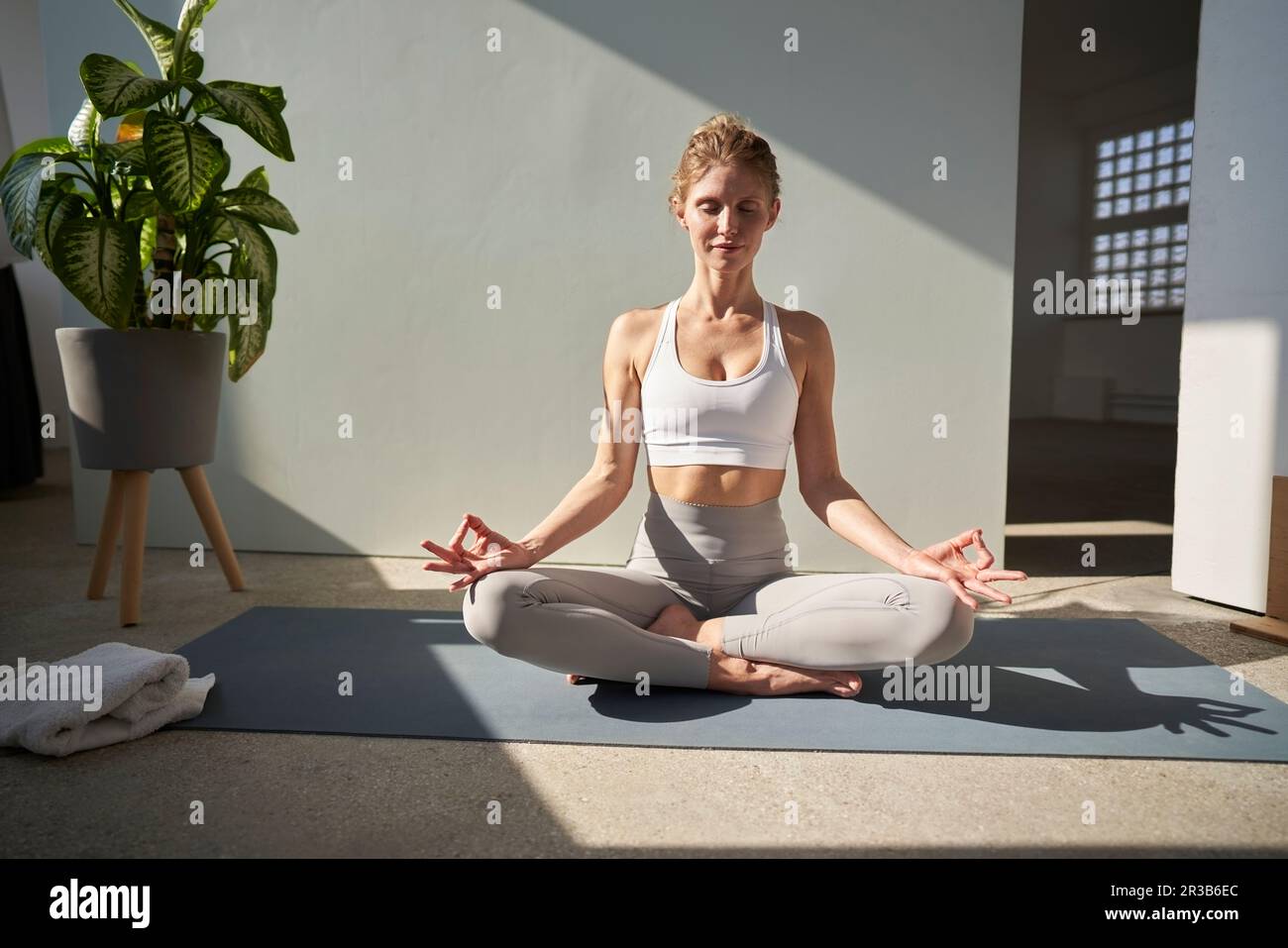 Woman practicing Lotus Position sitting cross-legged on mat Stock Photo ...