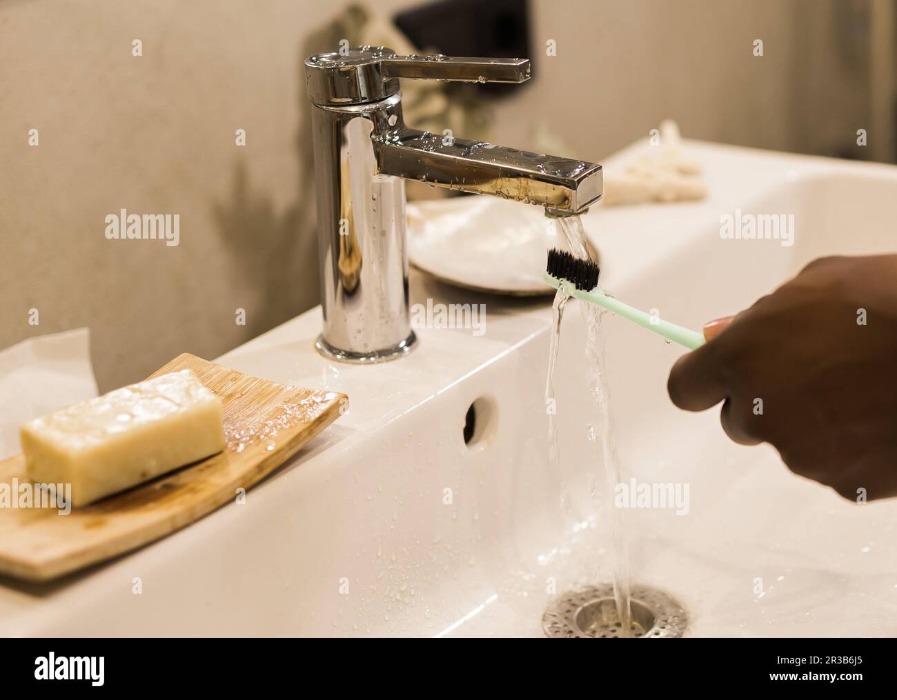 African american male hand holding toothbrush with toothpaste applied on it in bathroom. Close ...
