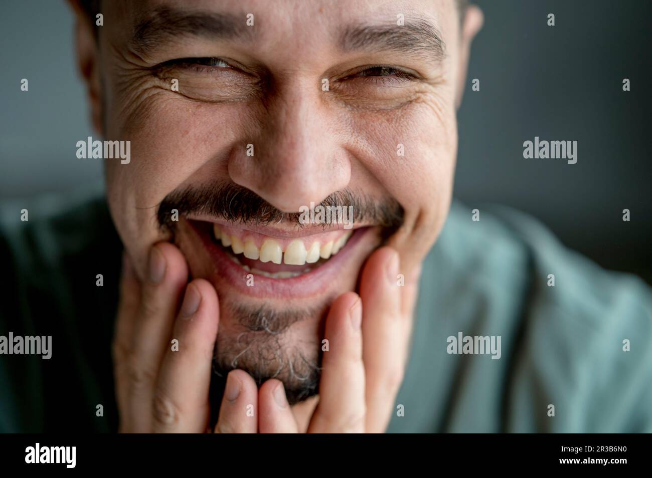 Happy man touching chin at home Stock Photo - Alamy