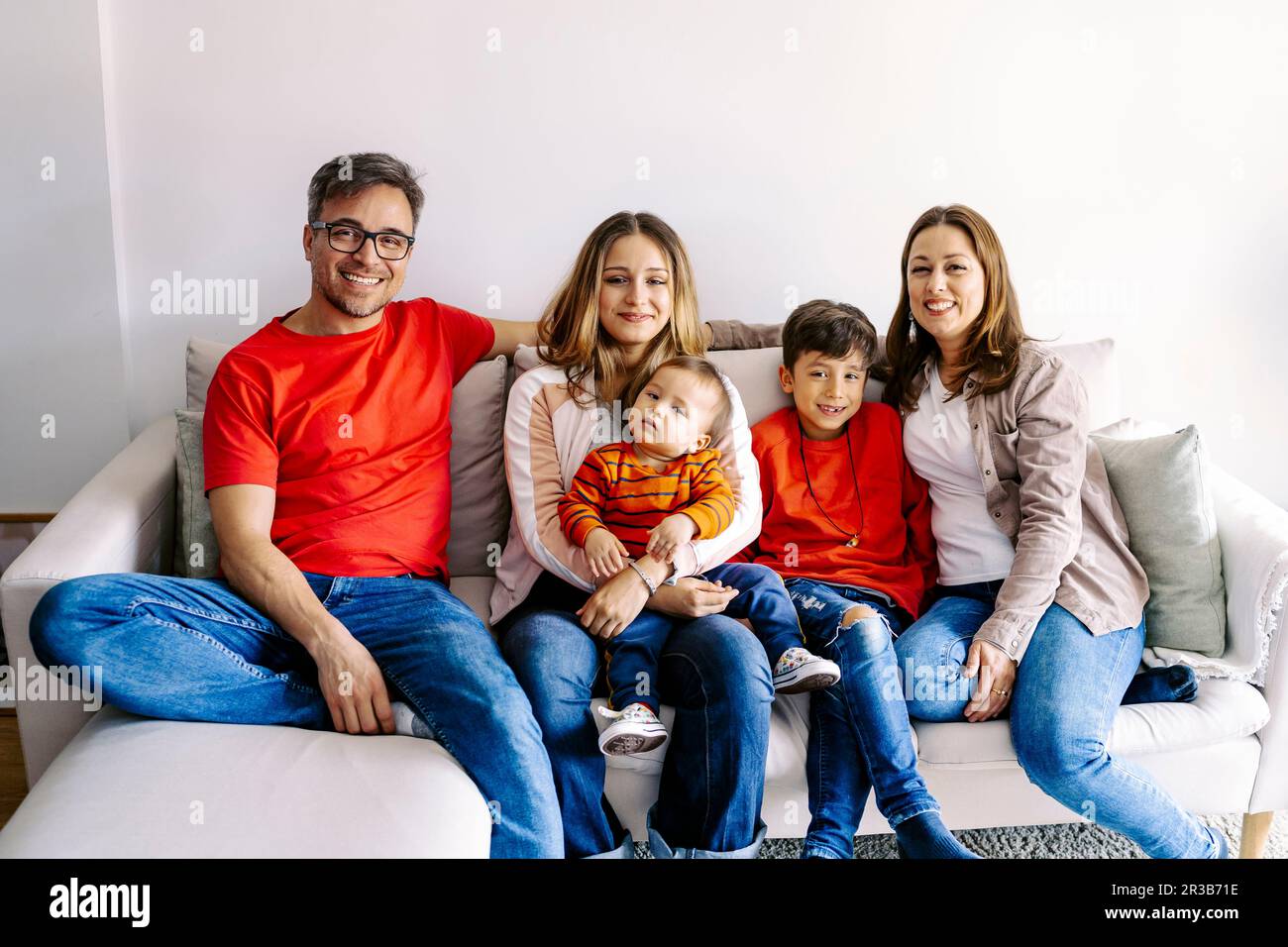 Smiling family sitting with children on sofa at home Stock Photo - Alamy
