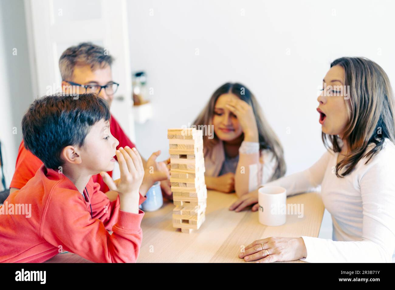 Mother and father playing block removal game with children at home ...