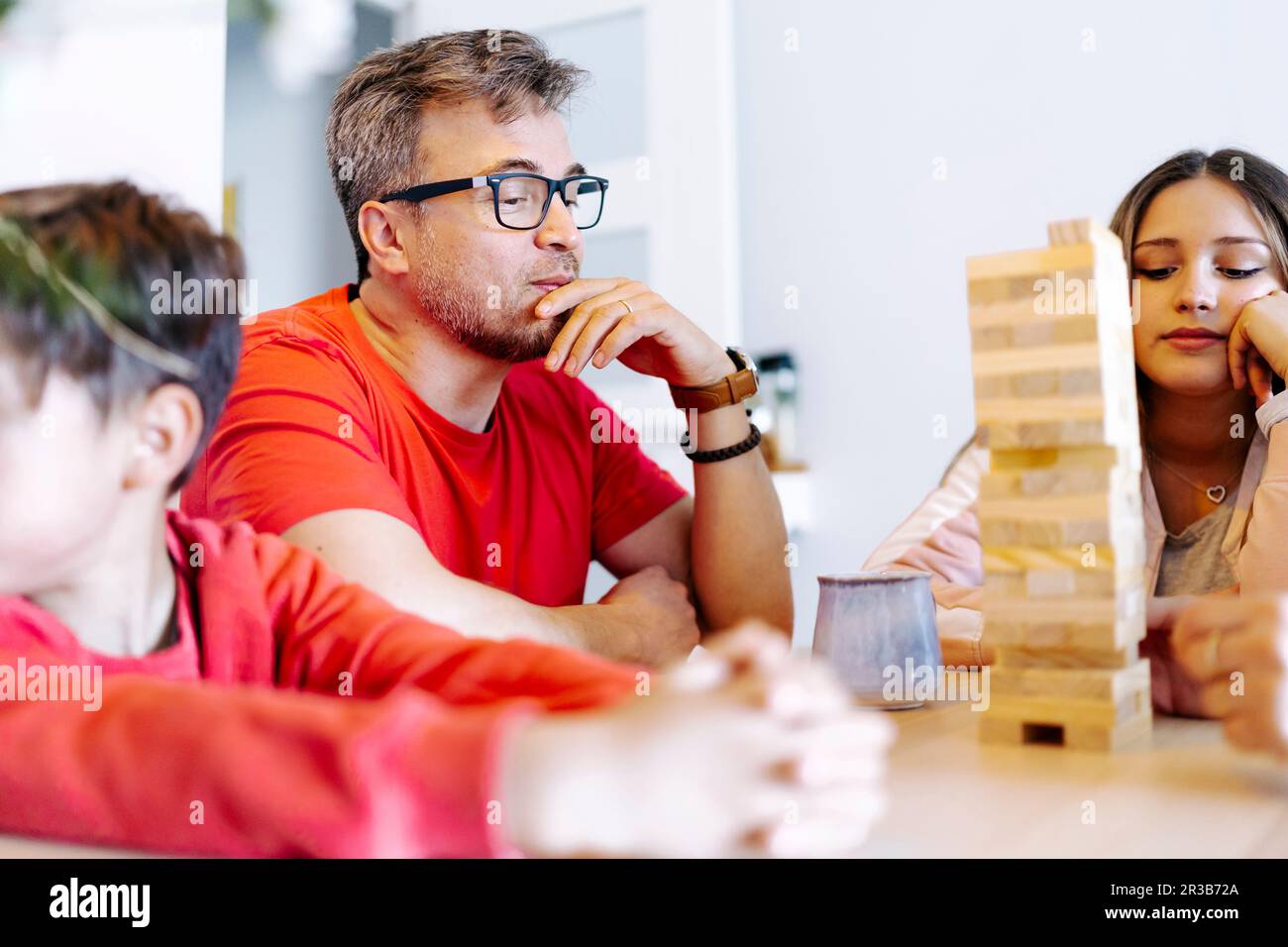 Thoughtful father playing block removal game with family at home Stock ...