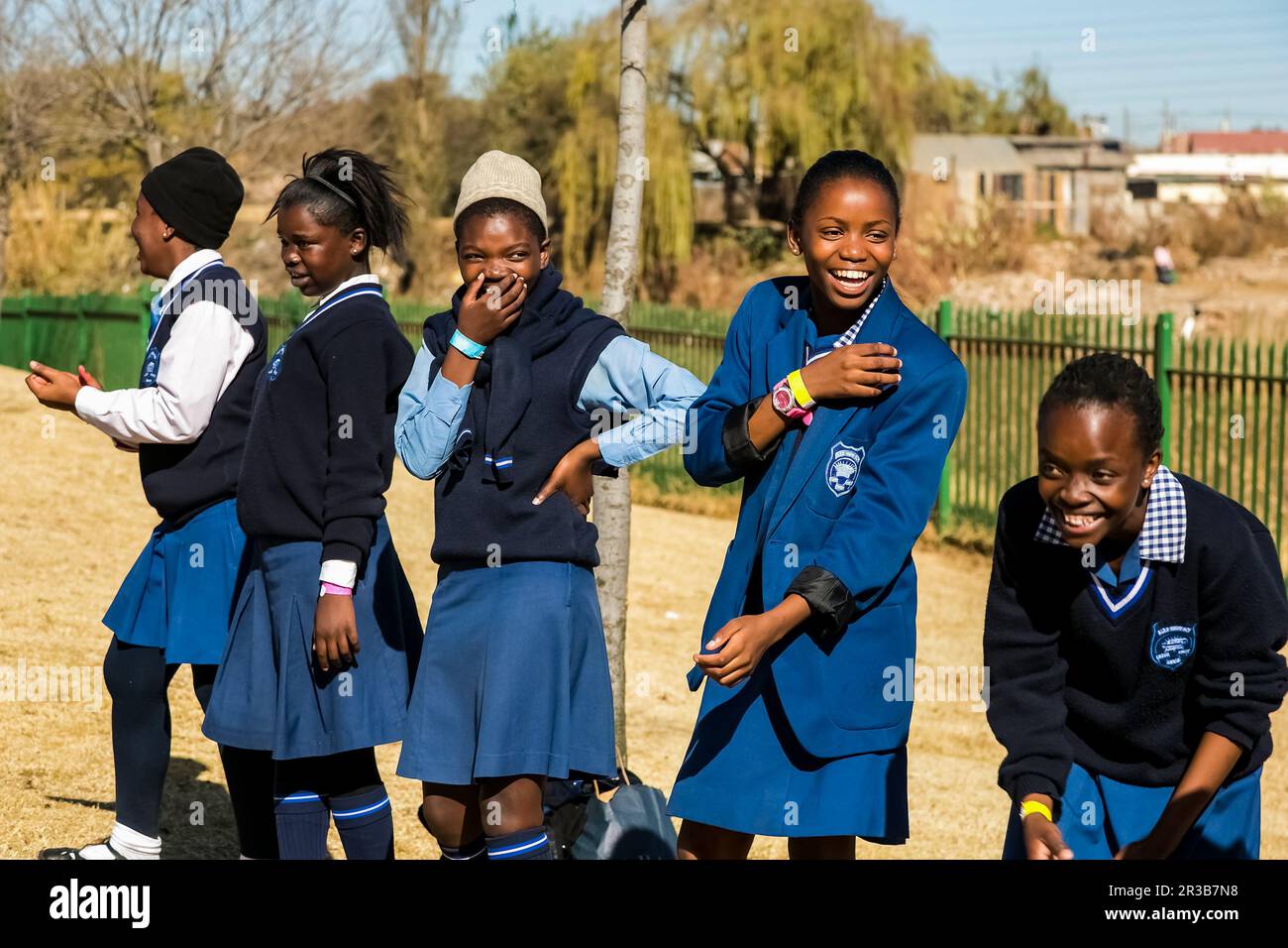Diverse African high school pupils messing about on the sports field ...