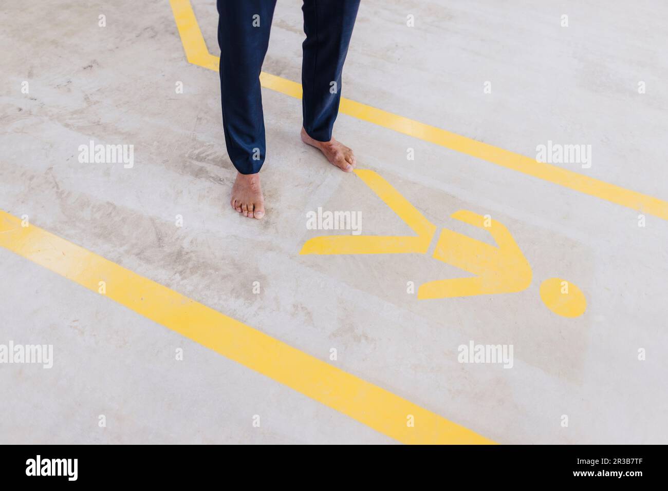 Businessman standing barefoot by sign on floor in factory Stock Photo ...