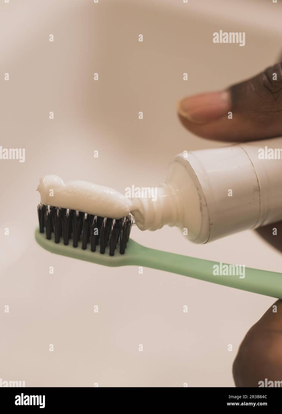 African american male hand holding toothbrush with toothpaste applied on it in bathroom. Close ...
