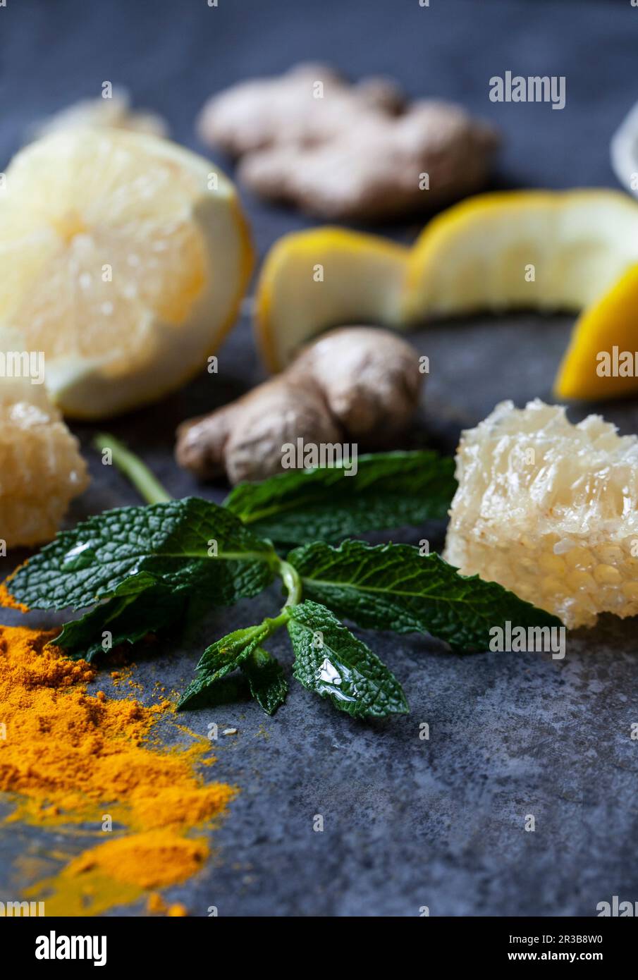 Lemon, ginger, turmeric powder, honeycomb and mint on a blue surface ...