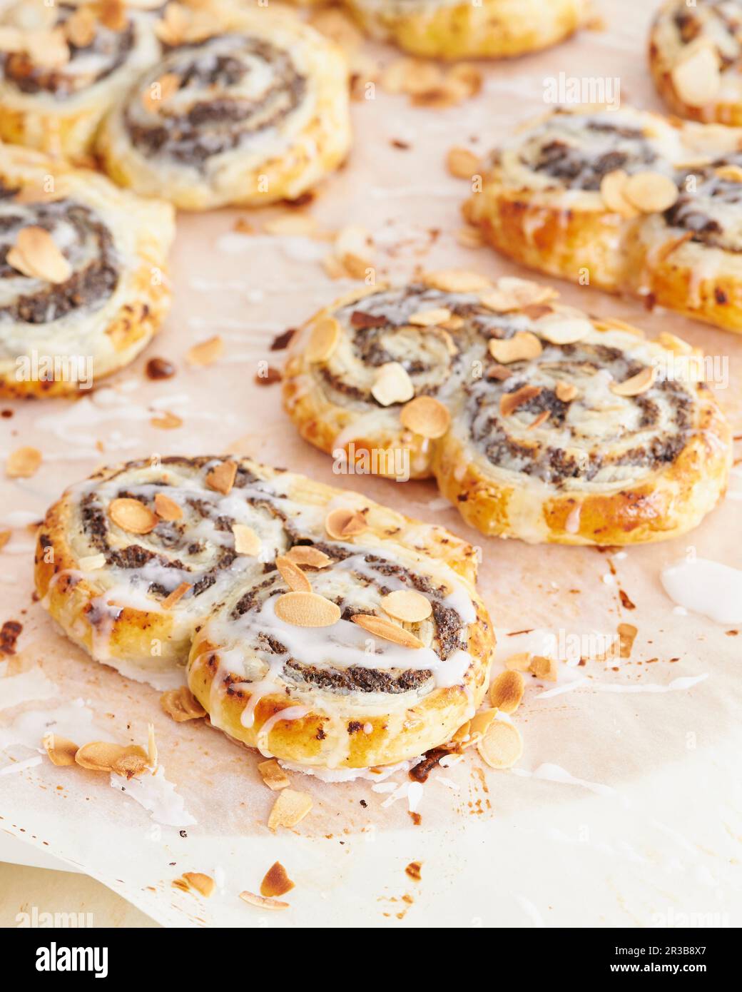 Poppy seed puff pastry buns with icing and flaked almonds Stock Photo ...