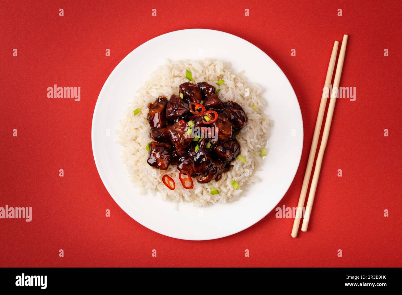 Sweet and sour meat stir fry in sticky sauce with rice on white plate ...