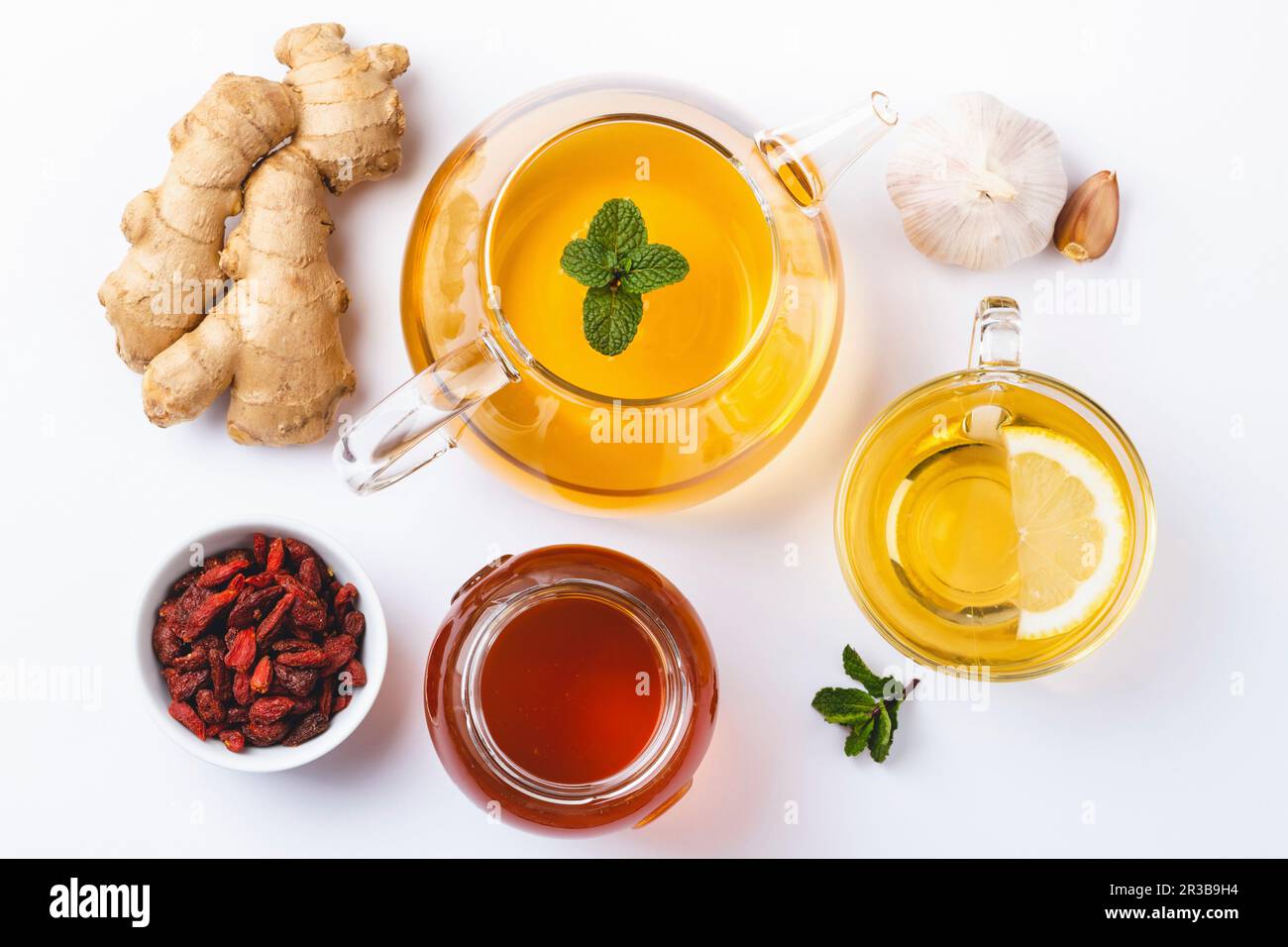 Homemade ginger and lemon tea, honey, goji, garlic, white background ...