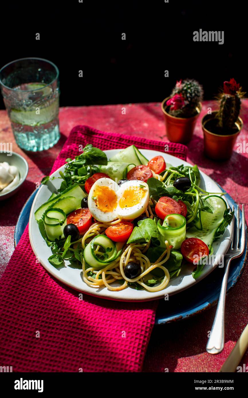 Spaghetti mit fresh cucumber, tomatoes and olives Stock Photo - Alamy