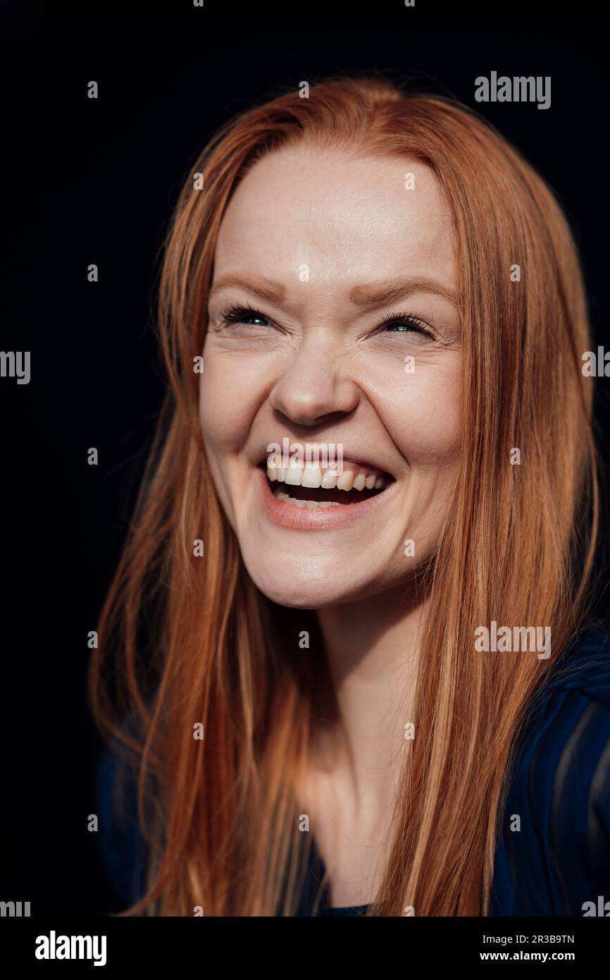Happy woman laughing against black background Stock Photo - Alamy