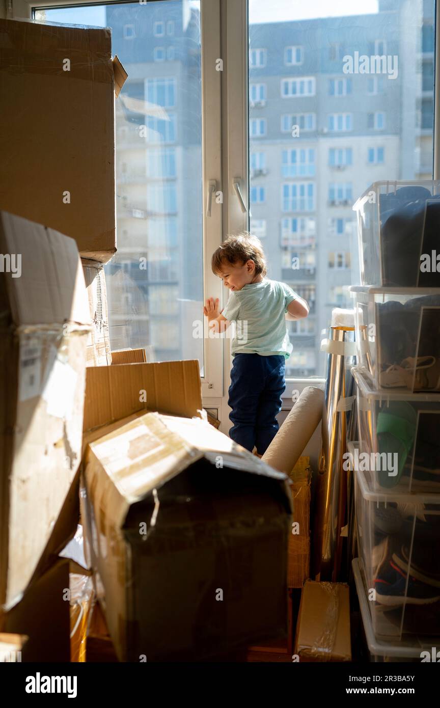 Boy standing amidst cardboard boxes at home Stock Photo - Alamy