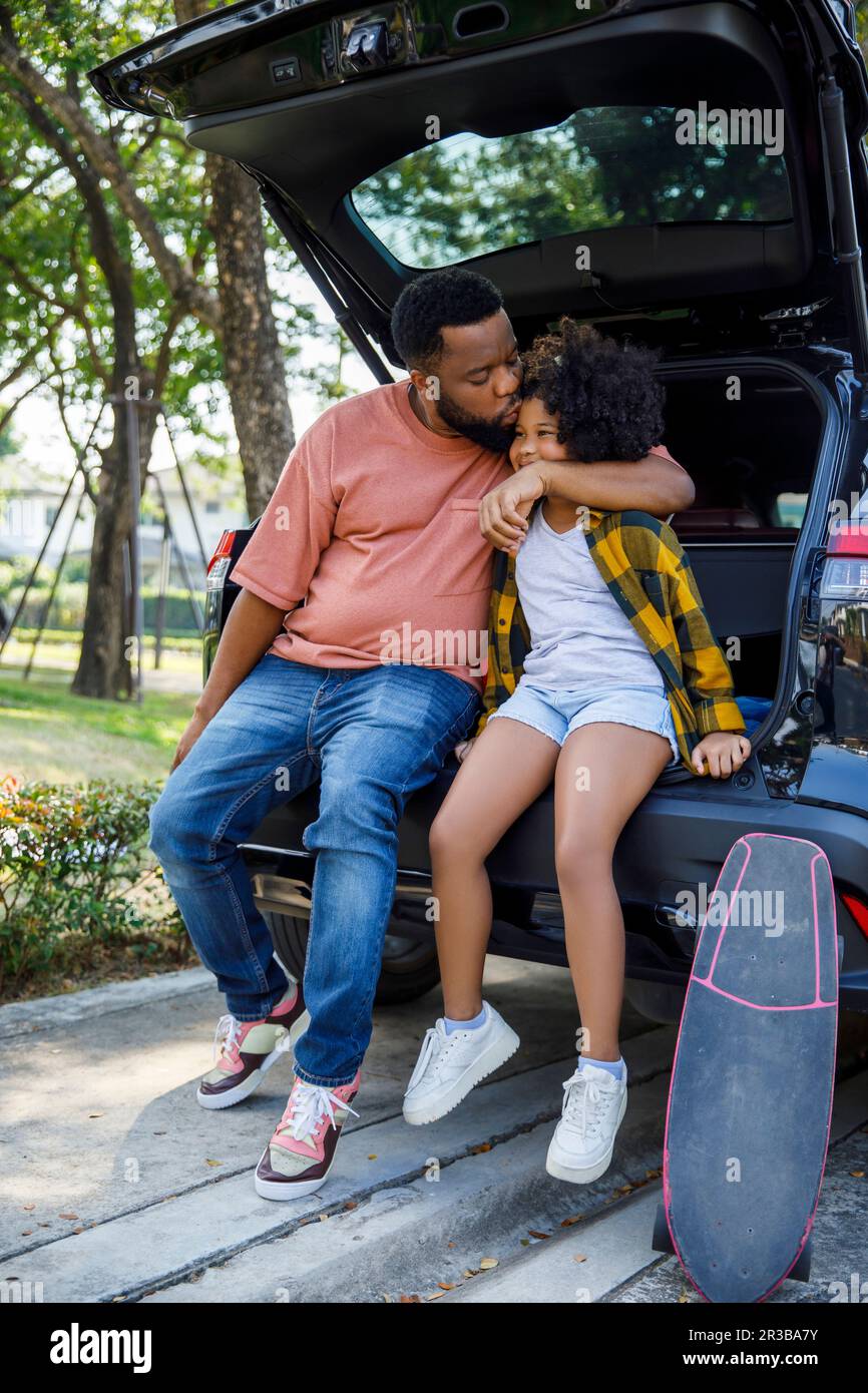 Father kissing daughter sitting on car trunk Stock Photo - Alamy