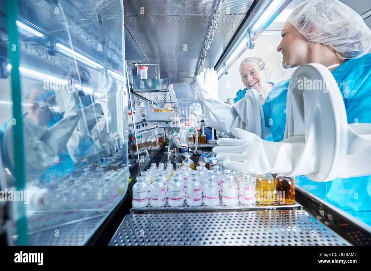Chemical workers giving high-five inside microbiological safety cabinet ...