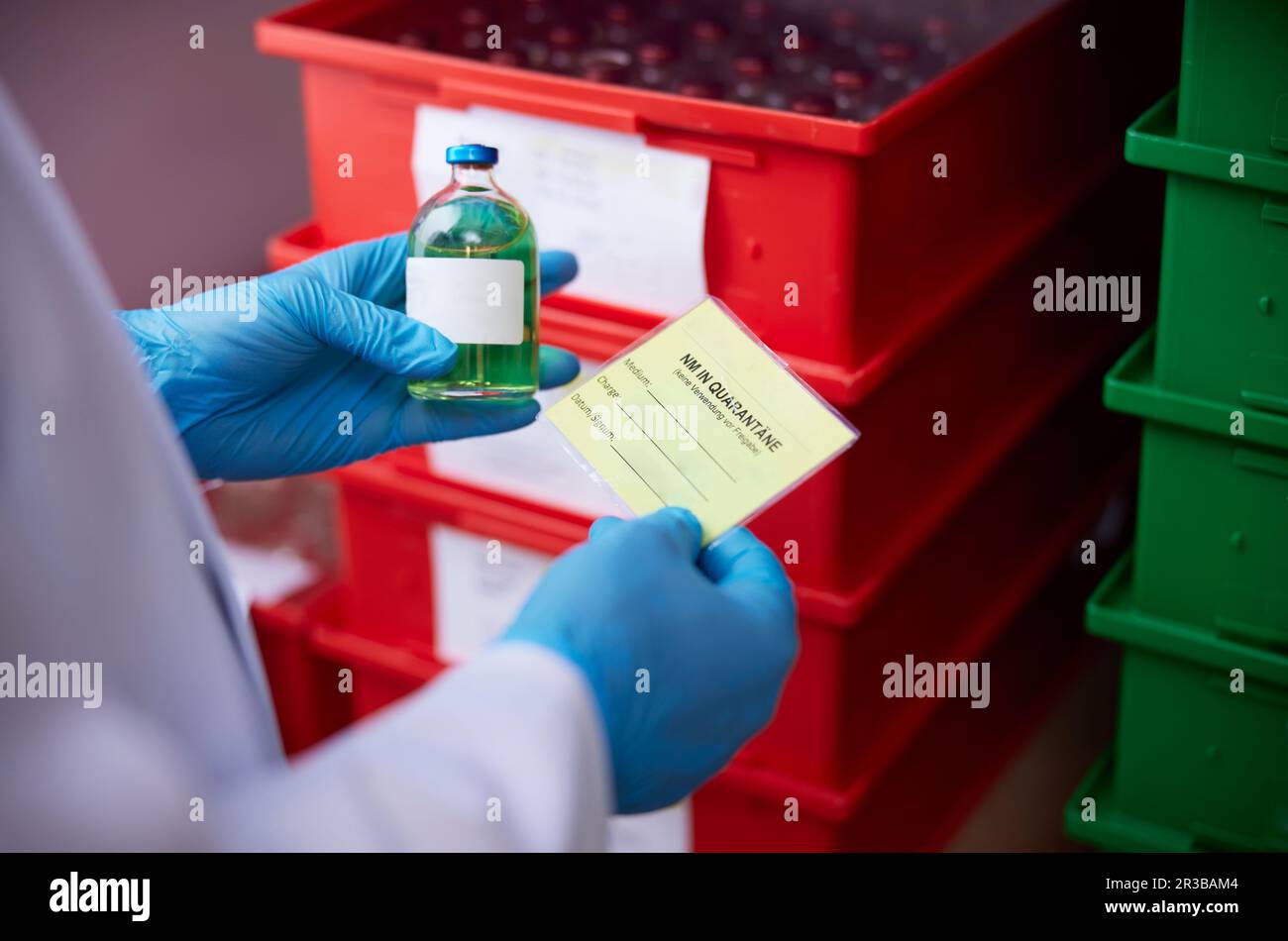 Hand of scientist examining chemical bottle in microbiological ...