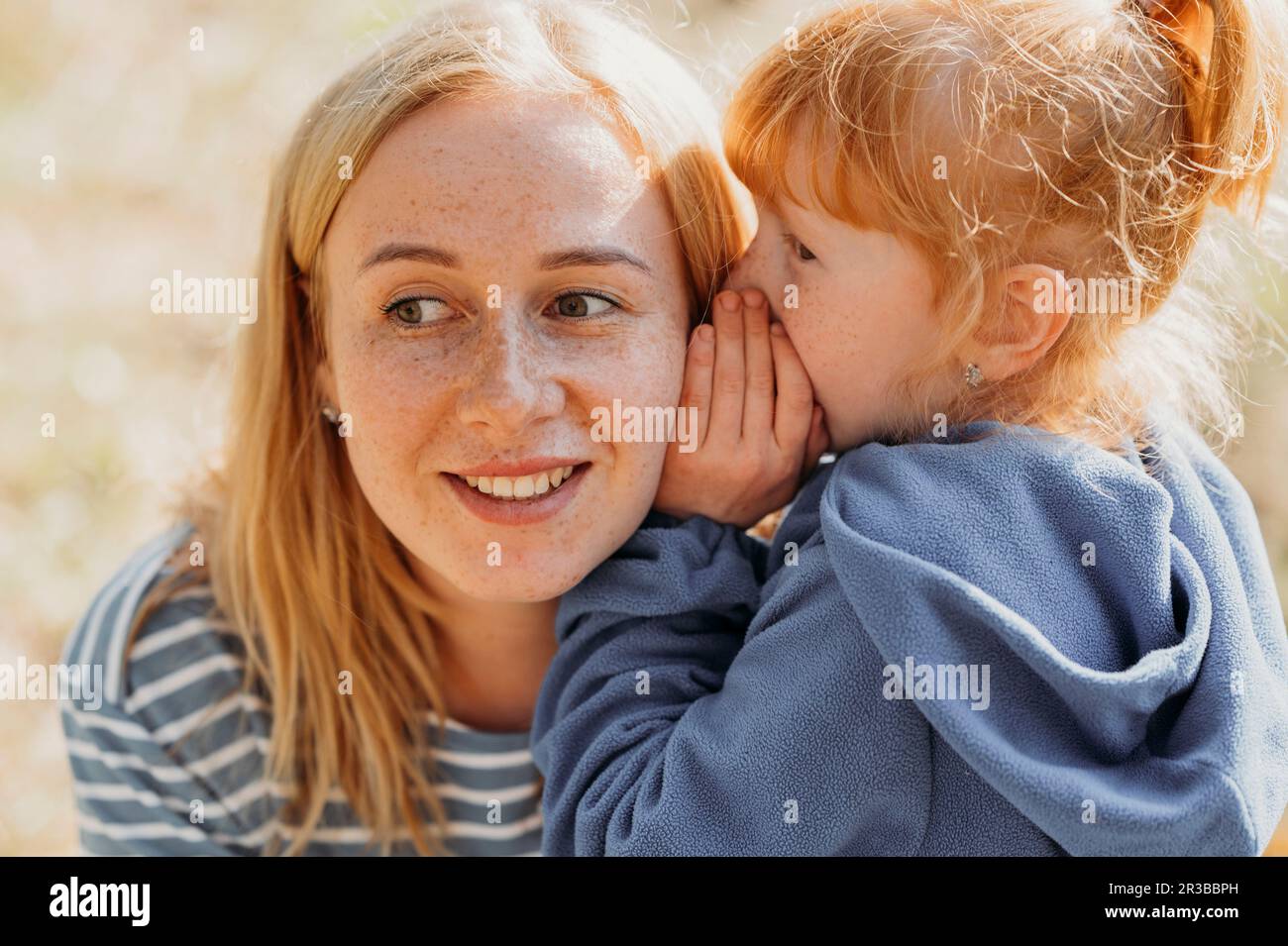 Daughter whispering secret in ear of mother Stock Photo - Alamy