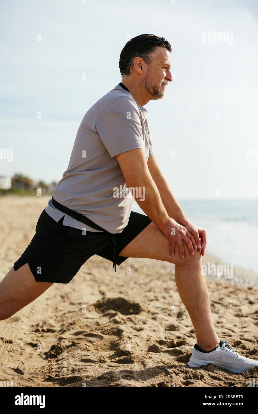 Mature man doing stretching exercise at beach Stock Photo - Alamy