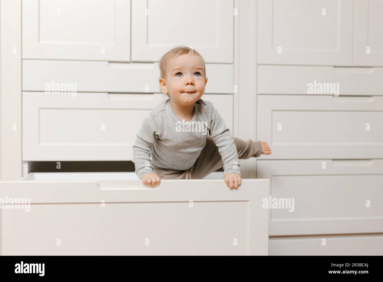 Baby boy coming out of wardrobe drawer at home Stock Photo - Alamy