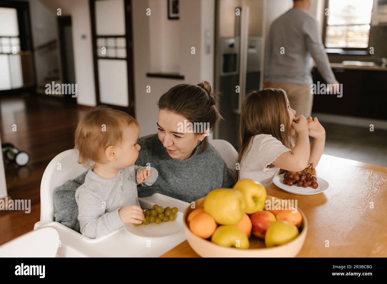 Mother with children eating fruit at dining table Stock Photo - Alamy