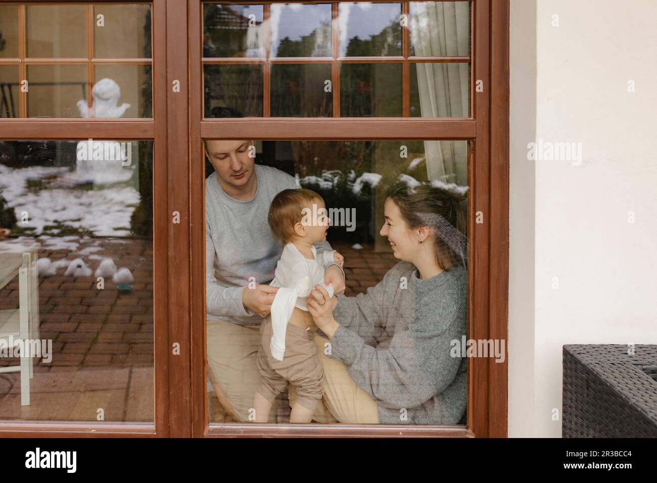 Family playing in house seen through glass window Stock Photo - Alamy