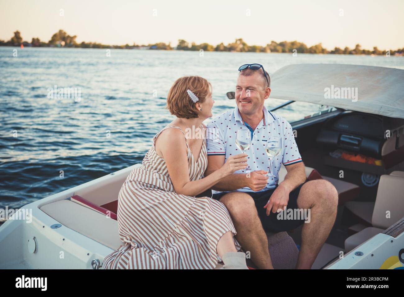 Beautiful couple man and woman drink wine while sitting in a boat ...