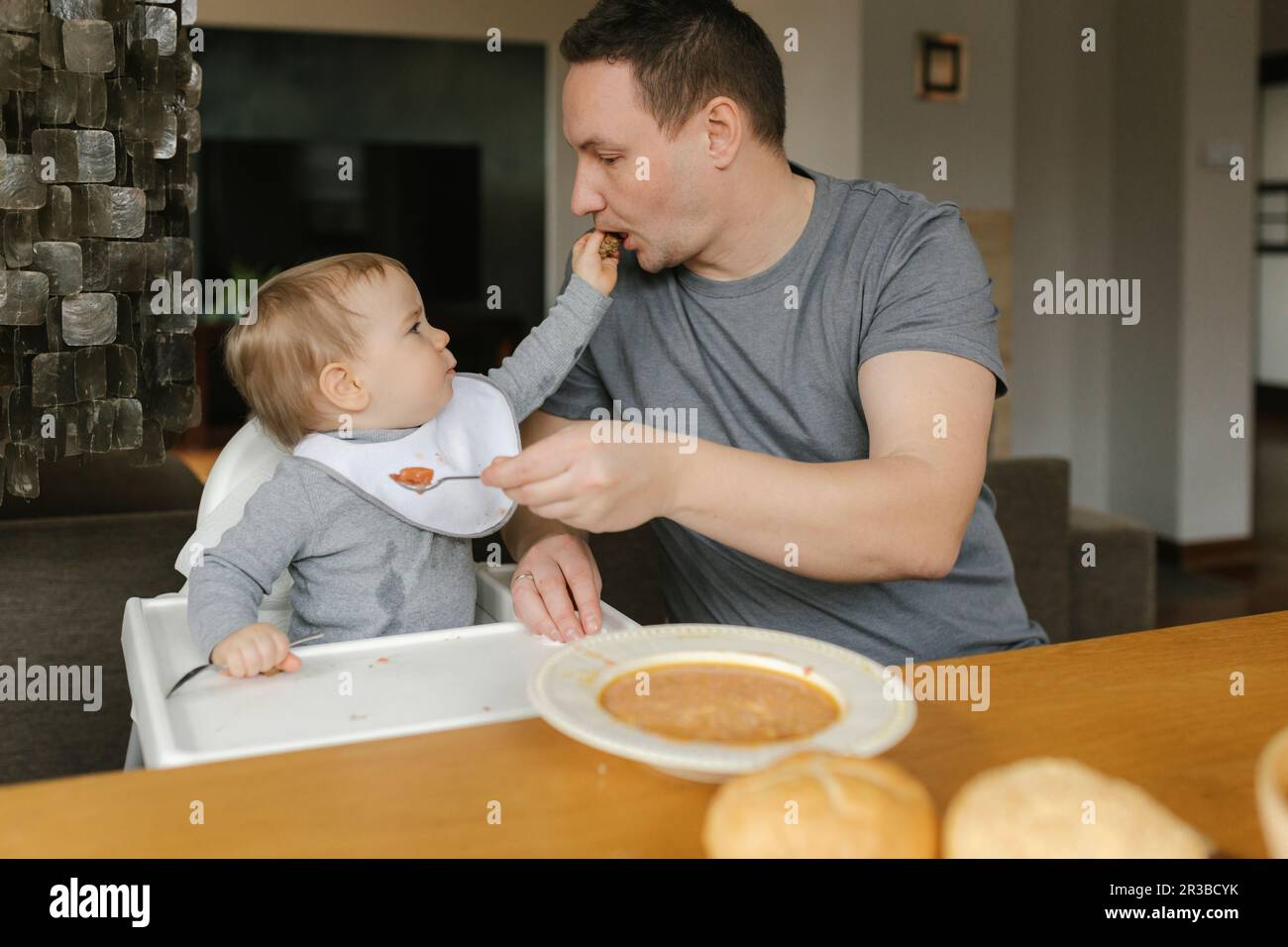Father feeding soup to baby boy at dining table Stock Photo - Alamy