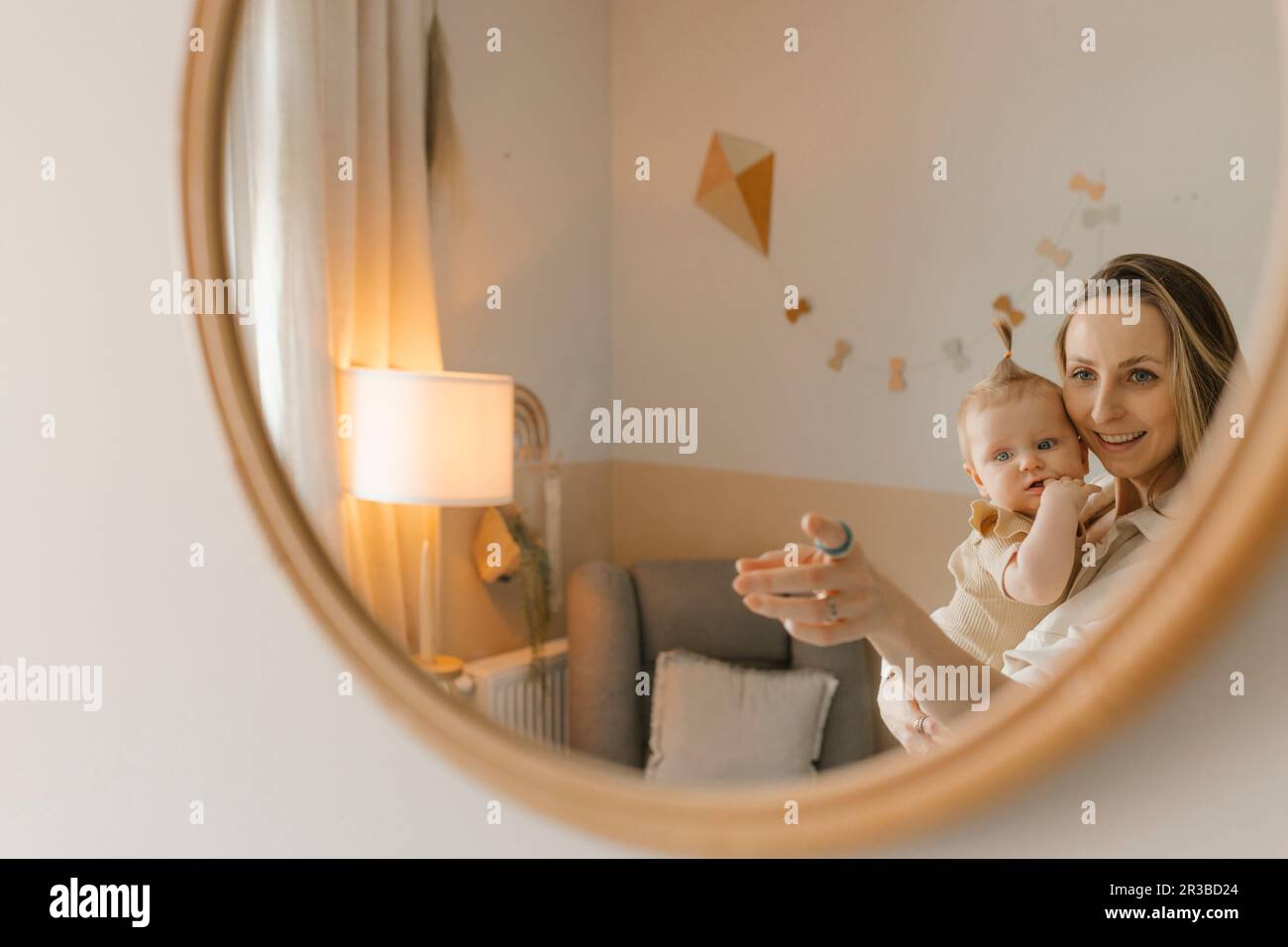 Happy mother carrying baby daughter reflecting in mirror at home Stock ...