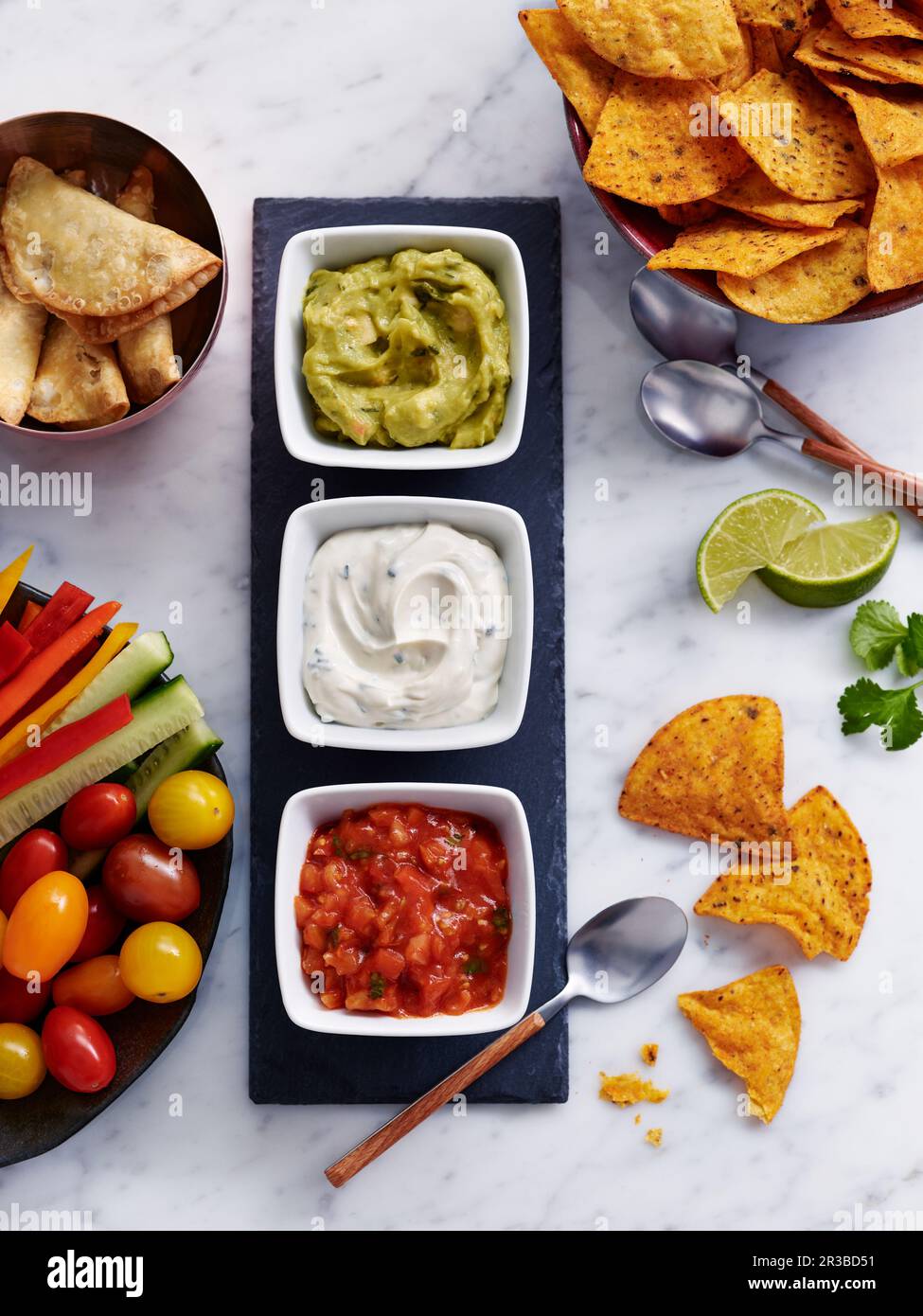 Guacamole, herb curd and salsa with nachos and vegetable sticks Stock ...
