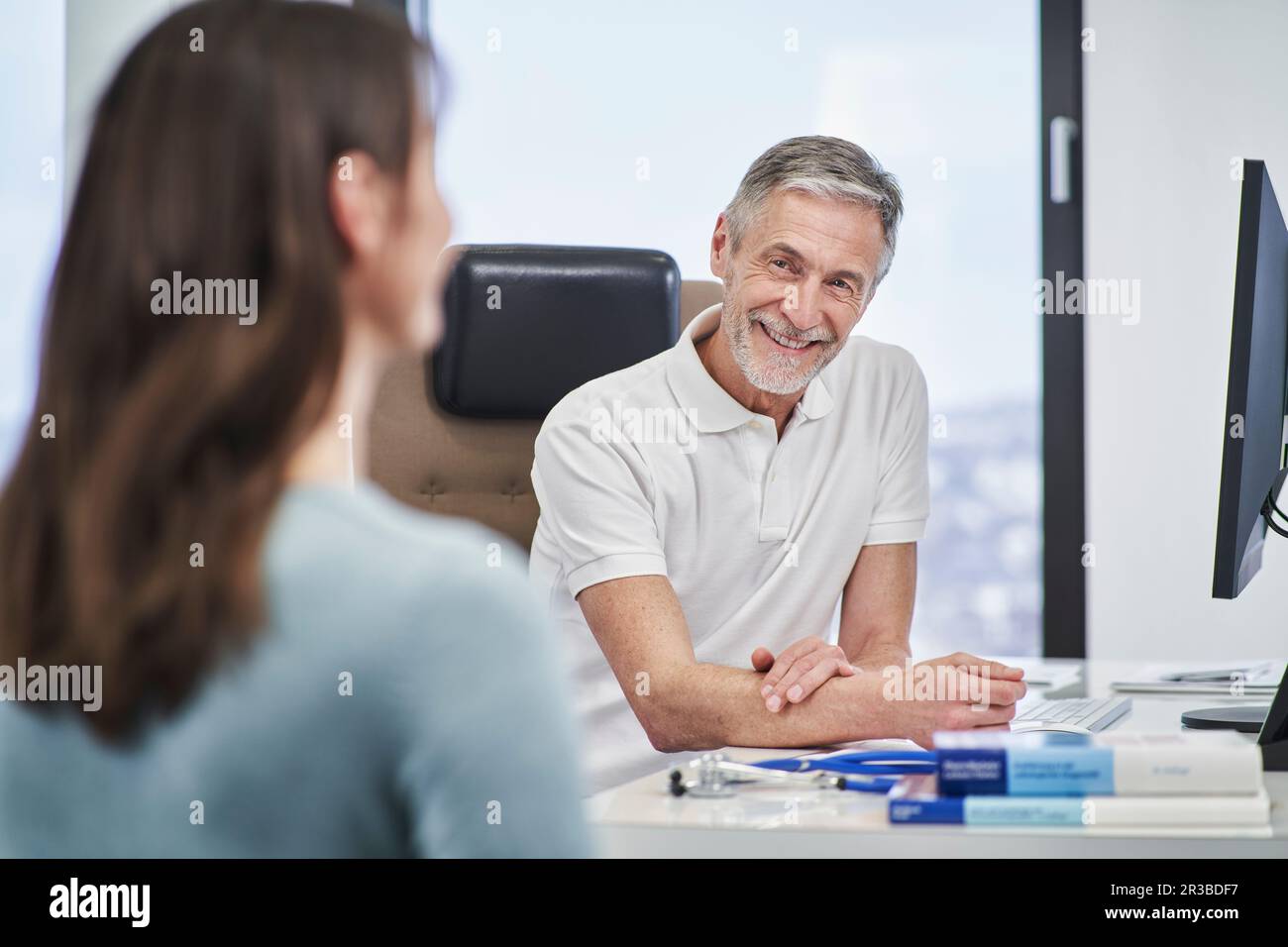 Doctor smiling at female patient in medical practice Stock Photo - Alamy