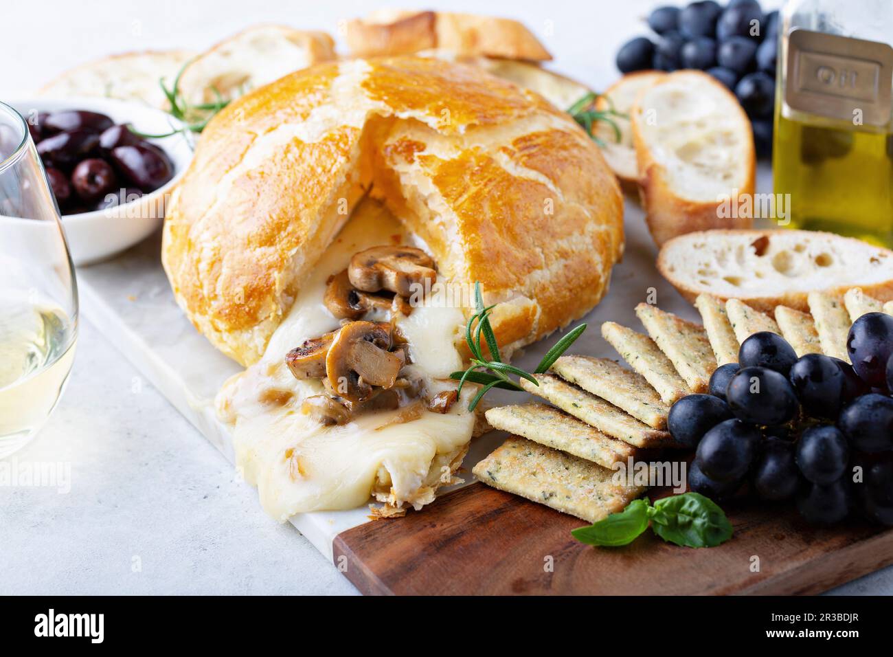 Baked brie wrapped in puff pastry with mushrooms with bread and cracker ...