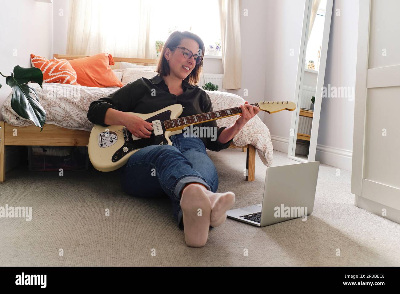 Woman learning guitar watching tutorial on laptop at home Stock Photo ...