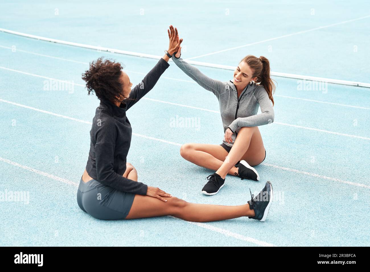 Happy woman, high five and partnership on stadium track for running ...