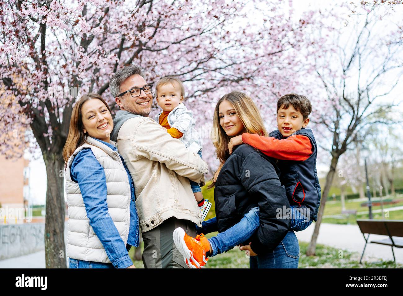 Happy family standing in front of cherry blossom tree Stock Photo - Alamy