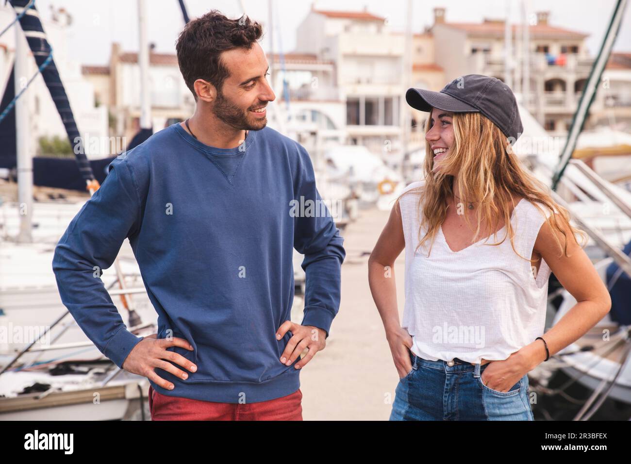 Smiling man with arms akimbo looking at girlfriend Stock Photo - Alamy