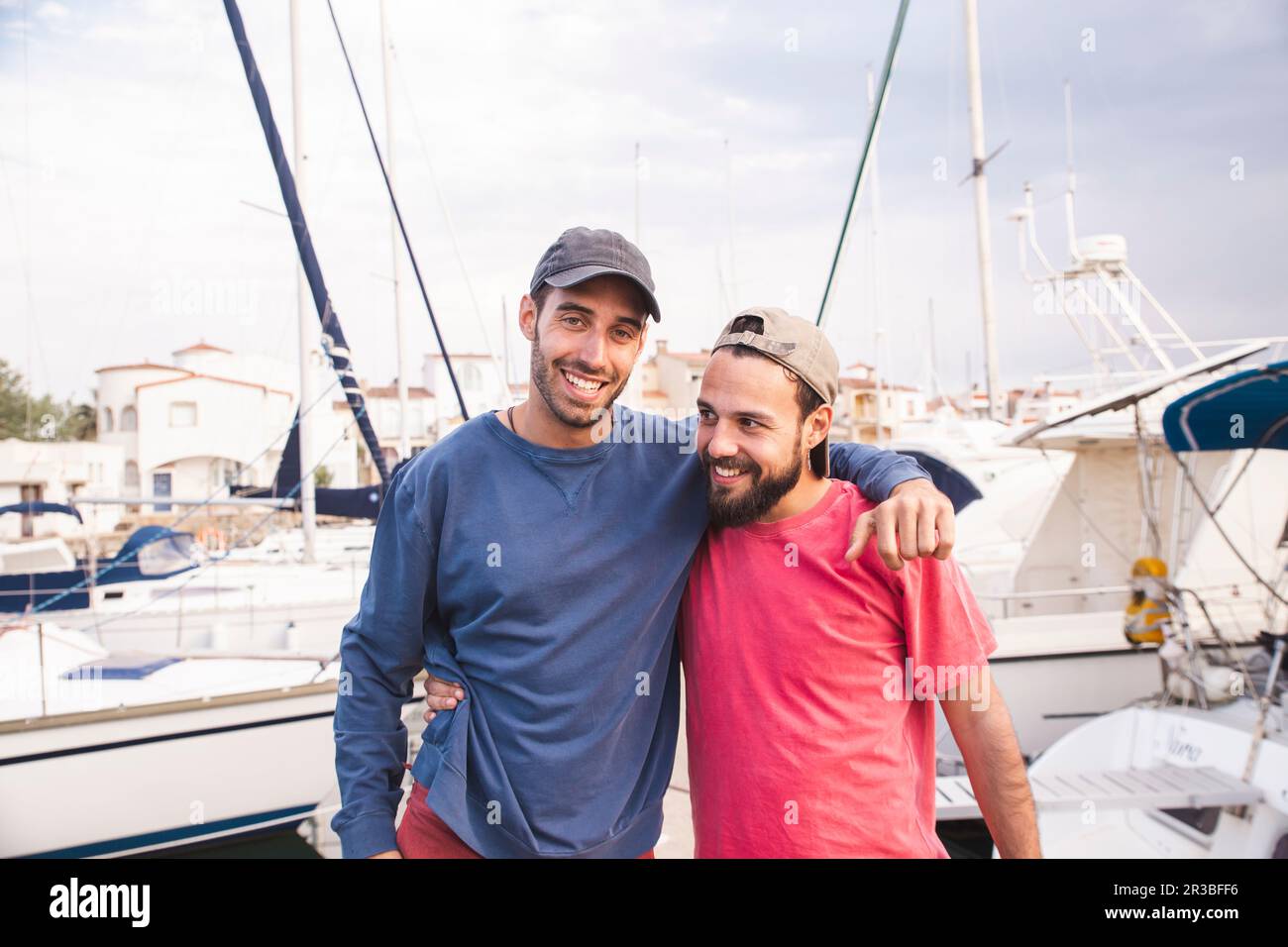 Happy friends with arms around each other standing at harbor Stock ...