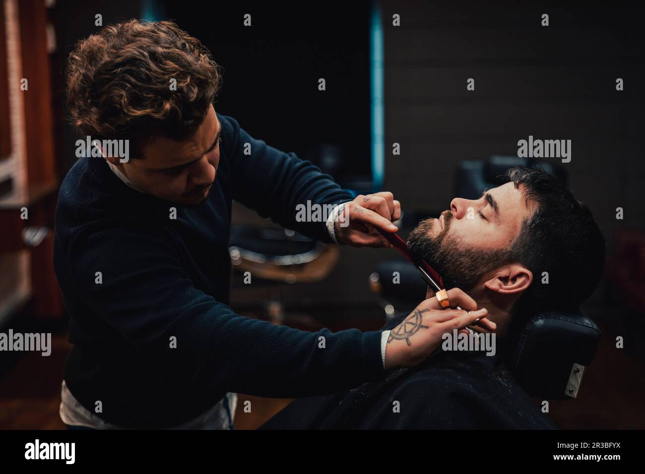 Barber cutting beard of customer in shop Stock Photo - Alamy