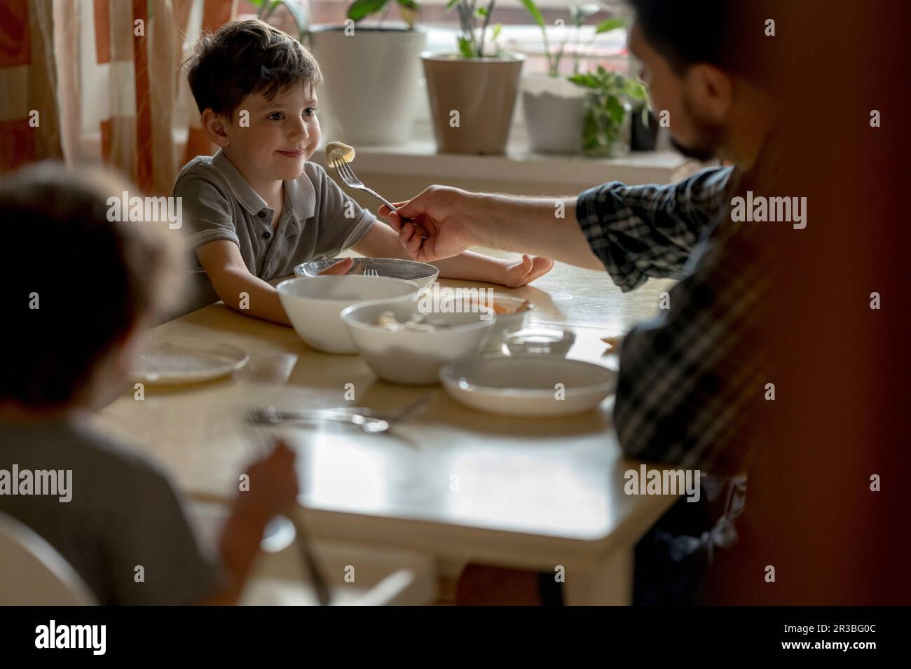 Father feeding dumpling to son at dining table in home Stock Photo - Alamy