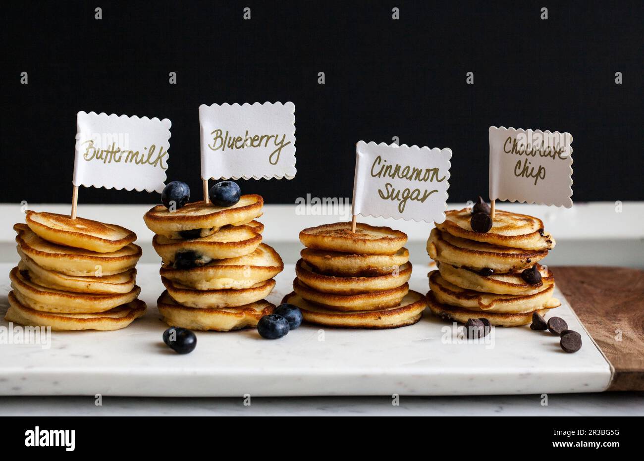Stacks of mini pancakes with signs, fruit and chocolate chips, on a ...
