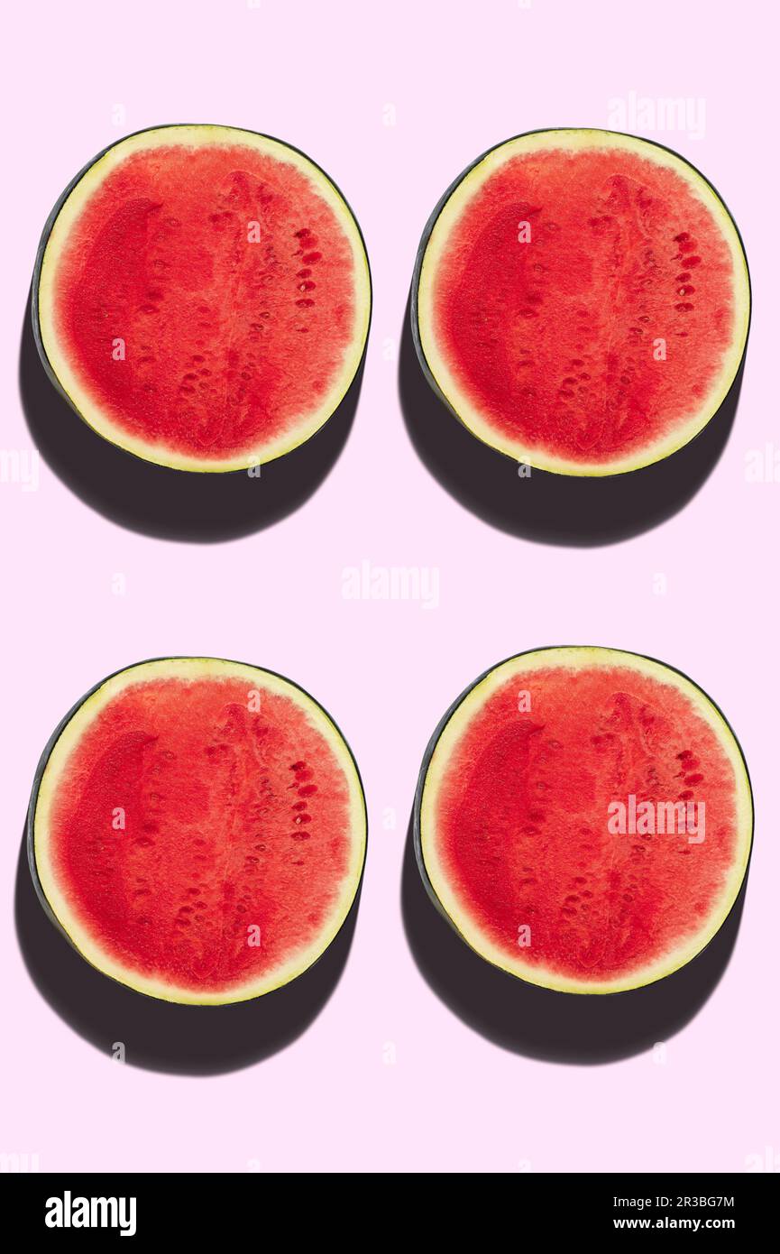 Four watermelon halves on a pink background Stock Photo - Alamy