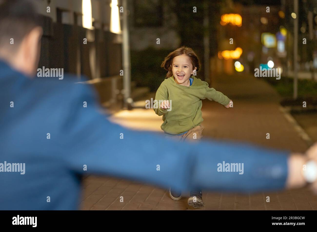 Cheerful son running towards father on sidewalk at night Stock Photo ...