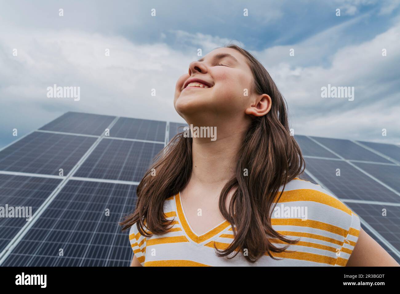 Smiling girl with eyes closed in front of solar panels Stock Photo - Alamy