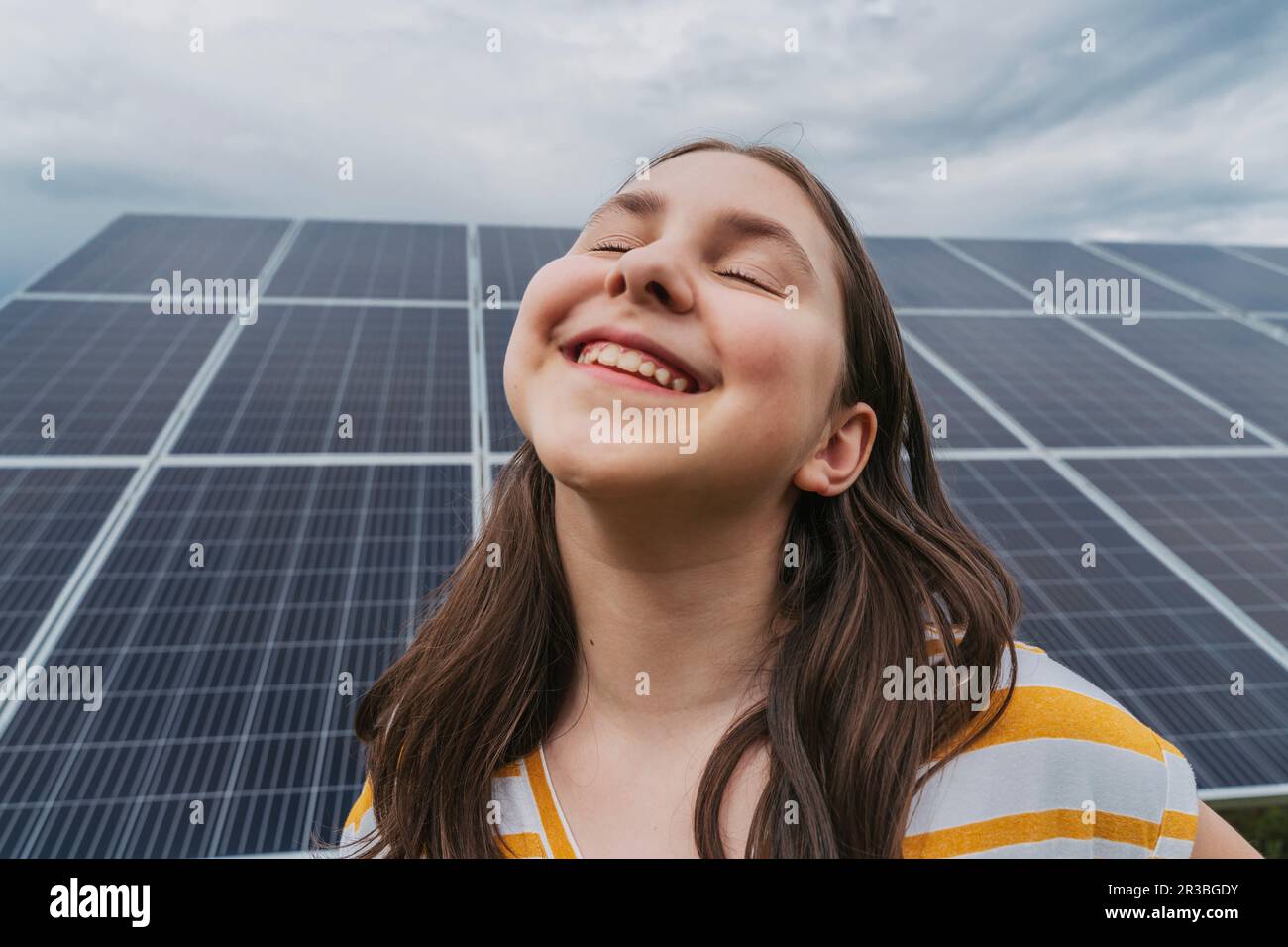 Happy girl with eyes closed in front of solar panels Stock Photo - Alamy