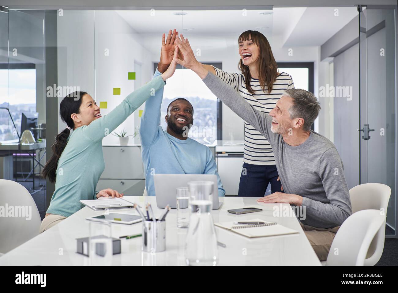 Happy colleagues giving high-five in office meeting Stock Photo - Alamy