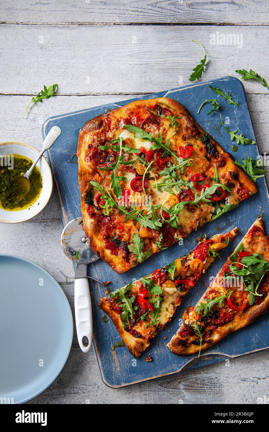 Homemade pizza with salami, mozzarella, sweet peppers, rocket and basil ...