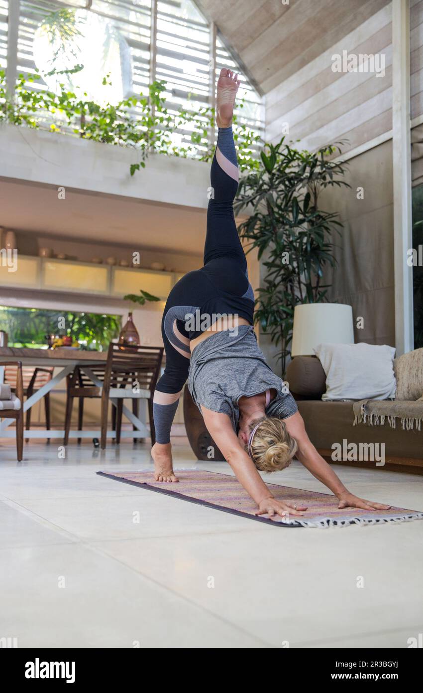 Woman practicing Standing Splits on exercise mat at home Stock Photo ...