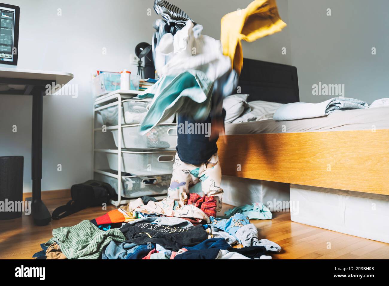 Toddler boy playing with cluttered clothes in bedroom at home Stock ...